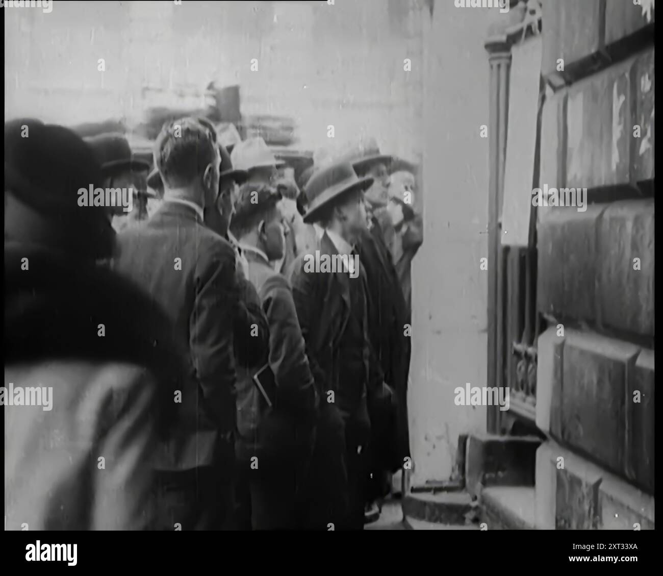 A Group of Male Civilians Looking at a Poster Attached to a Gate, 1926. From "Time To Remember ...
