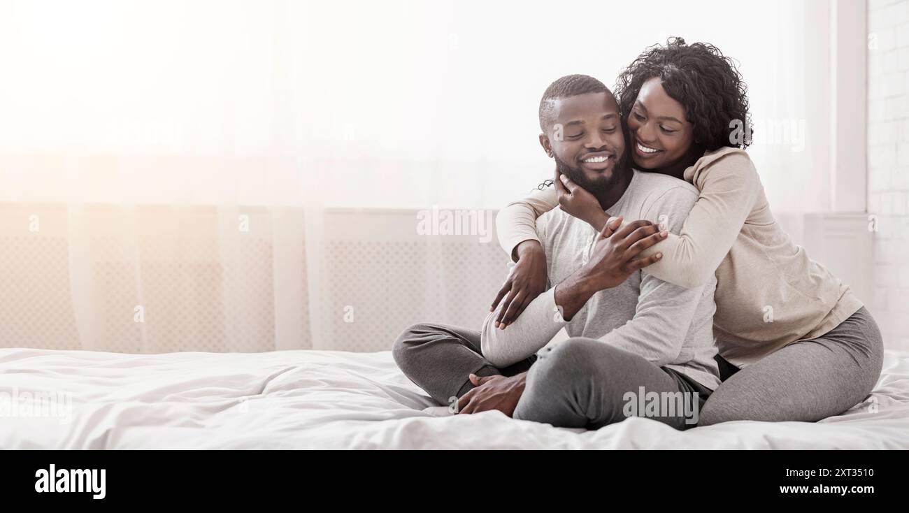Happy african american spouses cuddling on bed at home Stock Photo - Alamy