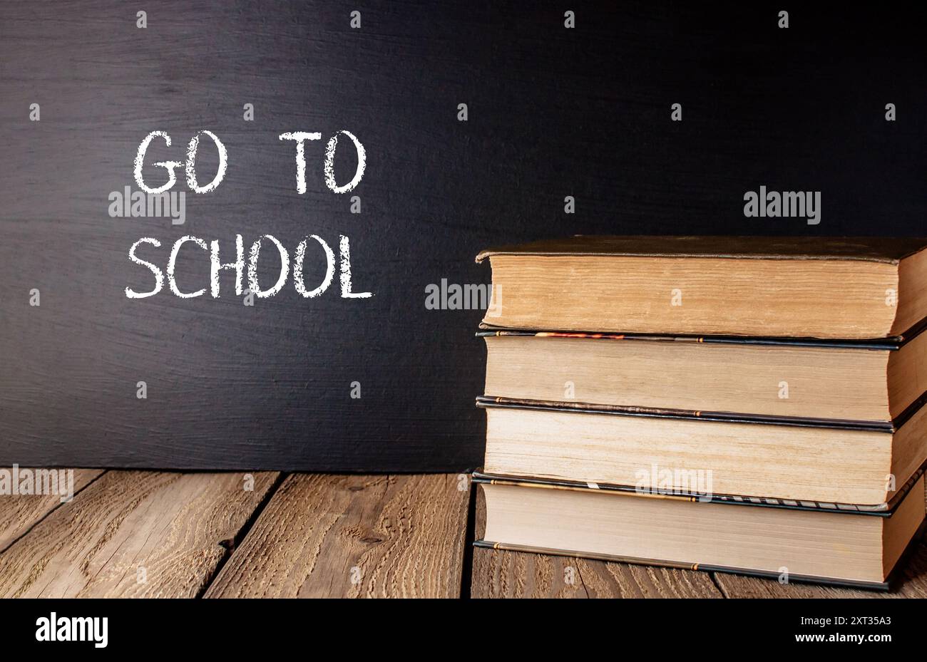 A stack of books with the words Go to School written on a chalkboard ...