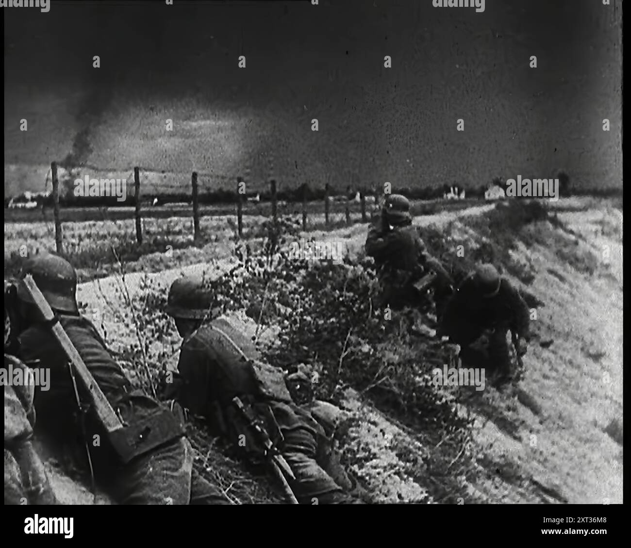 Four Male German Army Soldiers Lying Low on a Slope Below a Fence While ...