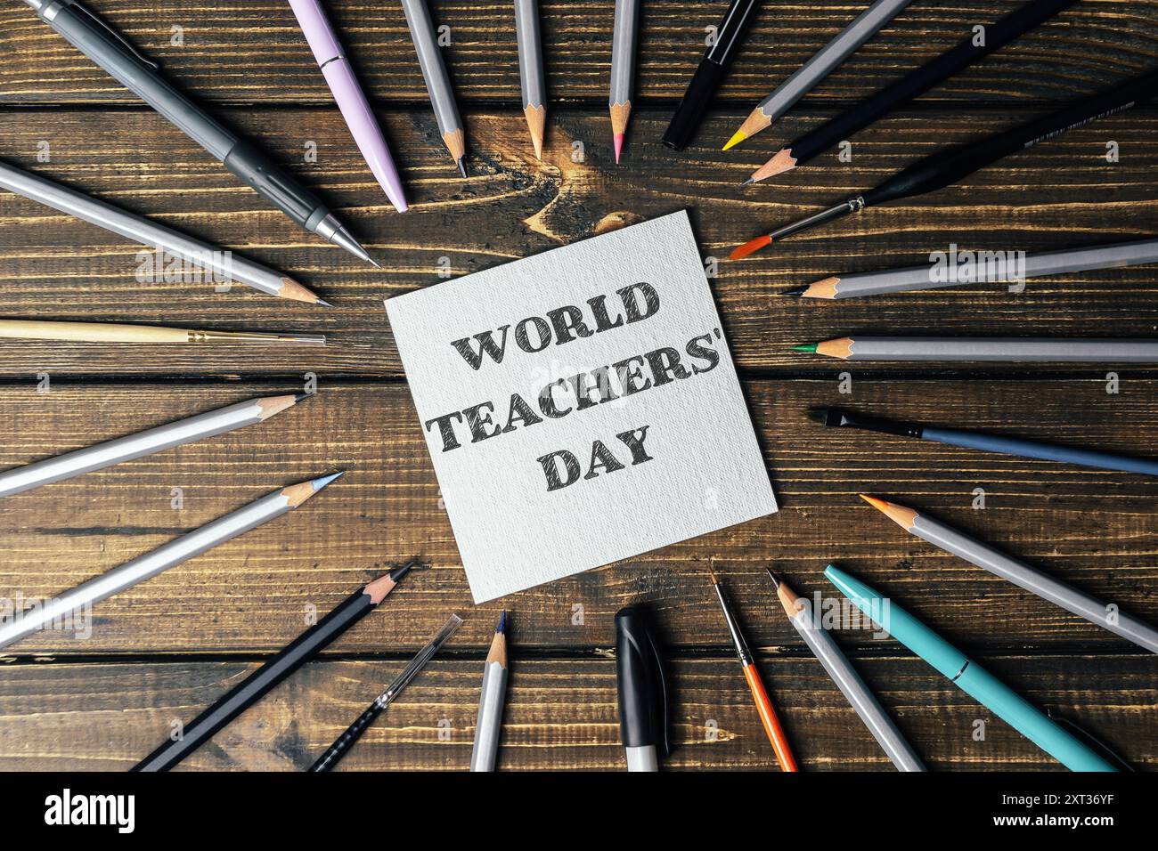 A collection of pencils and pens are arranged in a circle with the ...