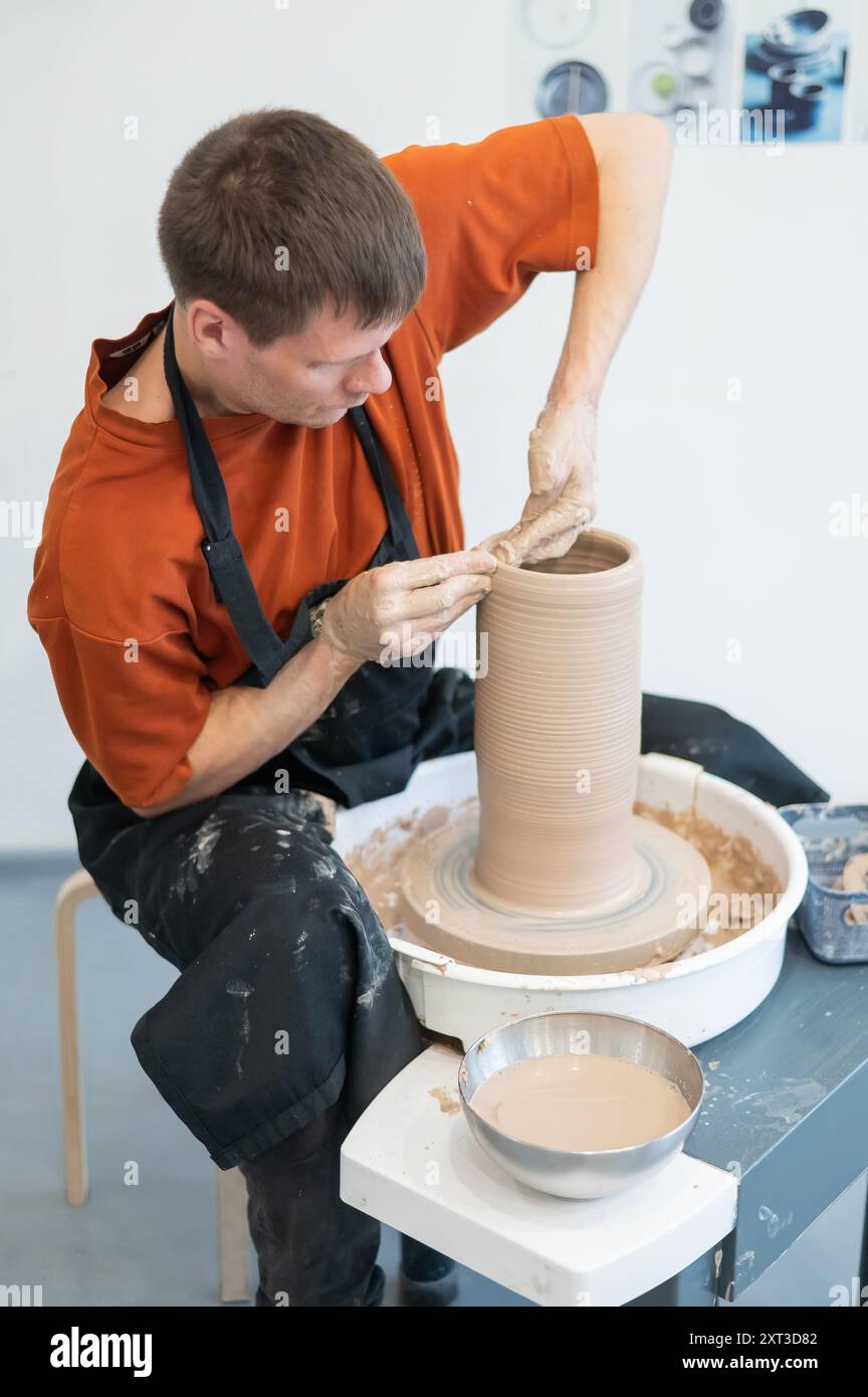 A potter works on a potter's wheel to smooth the surface of a vase ...