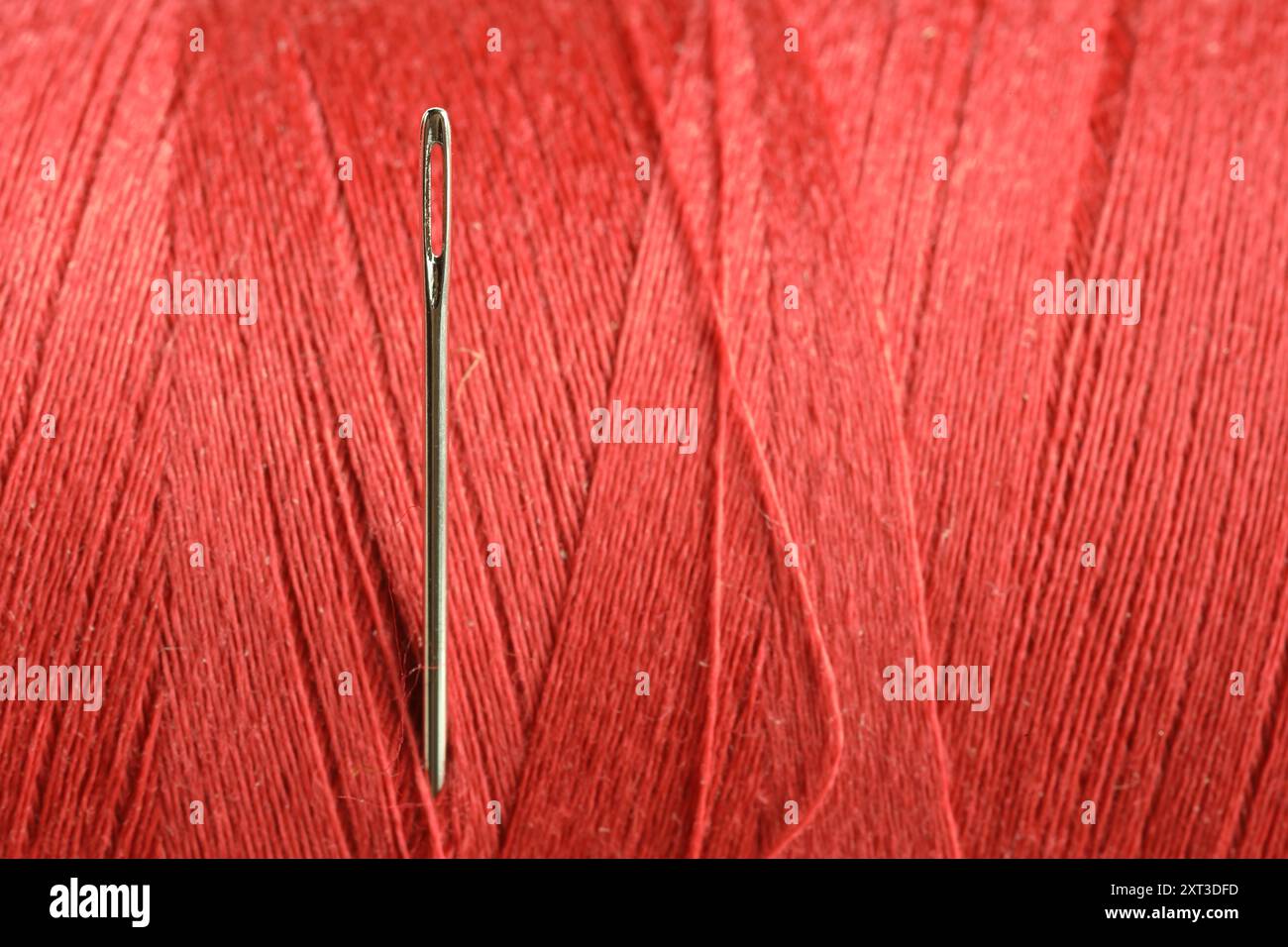 Spool of red sewing thread with needle, macro view Stock Photo - Alamy