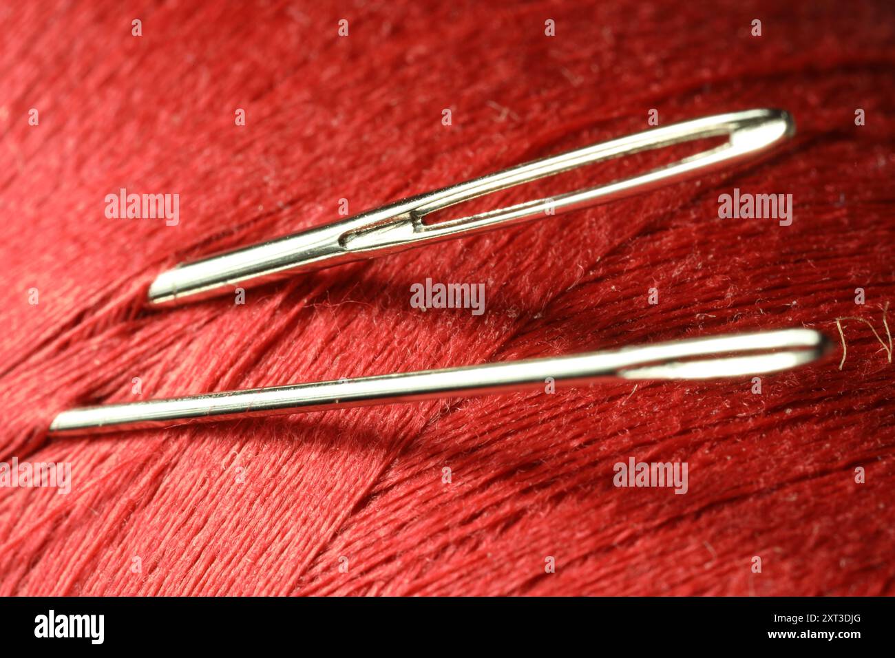 Spool of red sewing thread with needles, macro view Stock Photo - Alamy