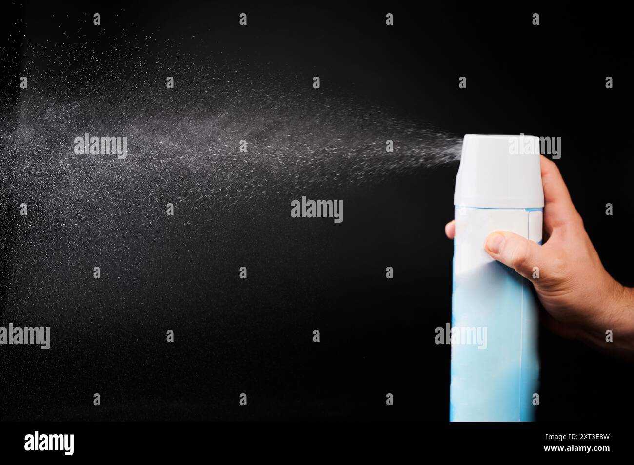 Hand hold metal spray bottle with air stream isolated on black studio ...