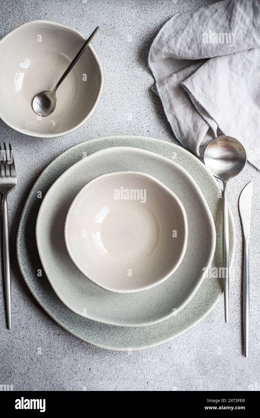 A minimalist table elegantly set with gray ceramic plates, stainless ...