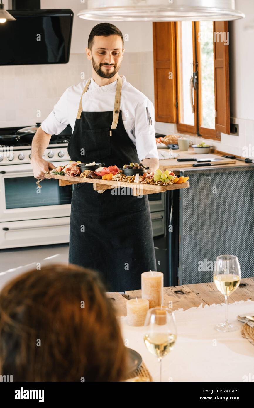 A male private chef, with his eyes looking down, is serving a gourmet ...