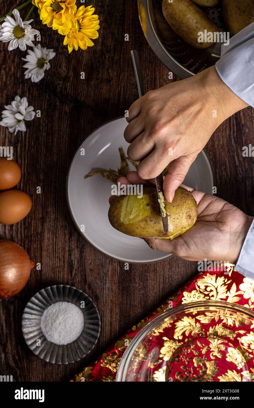 Top view of cropped unrecognizable person slicing a cooked potato on a ...