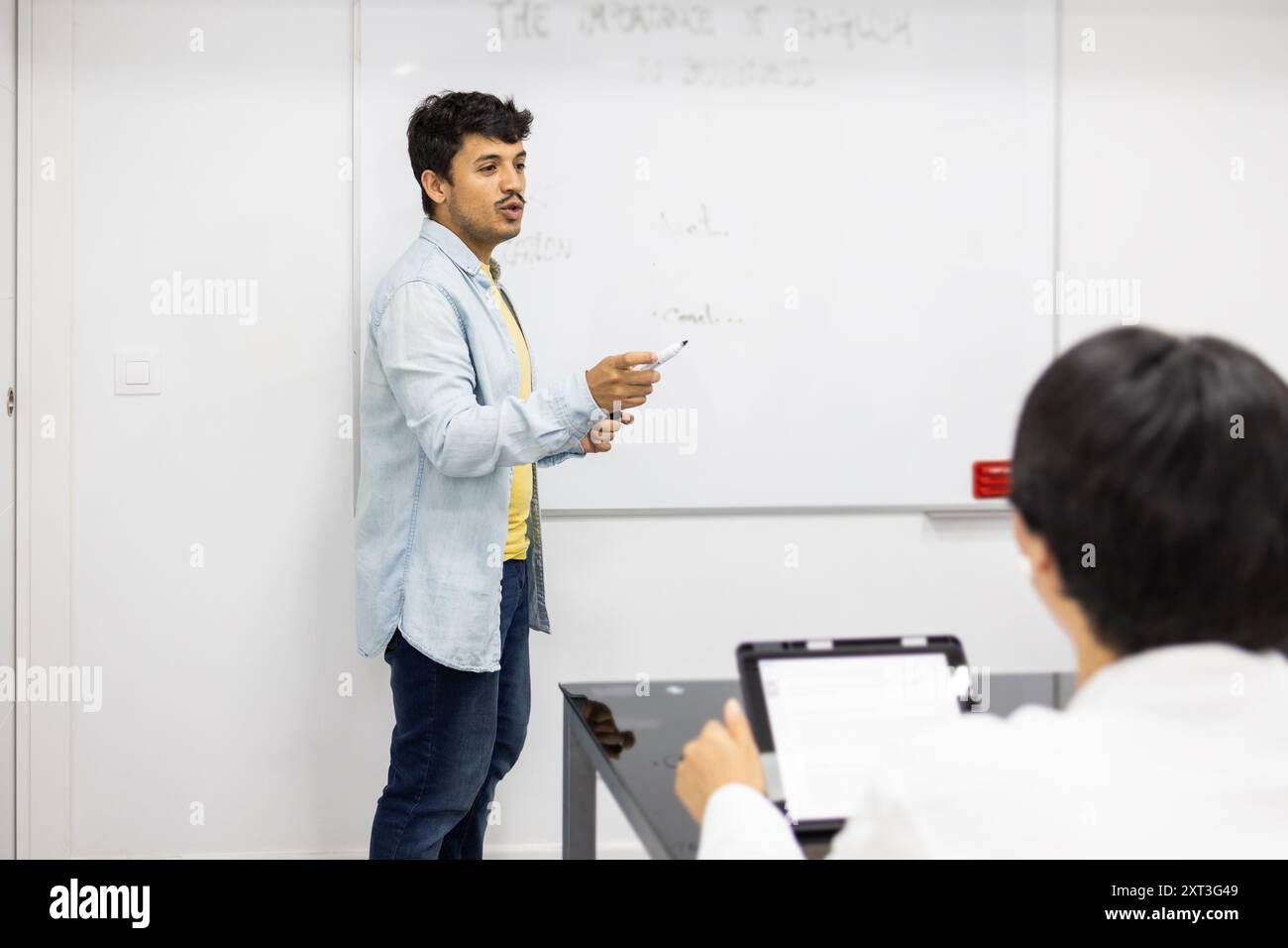 A male teacher conducts a lesson while engaging with his students in a ...
