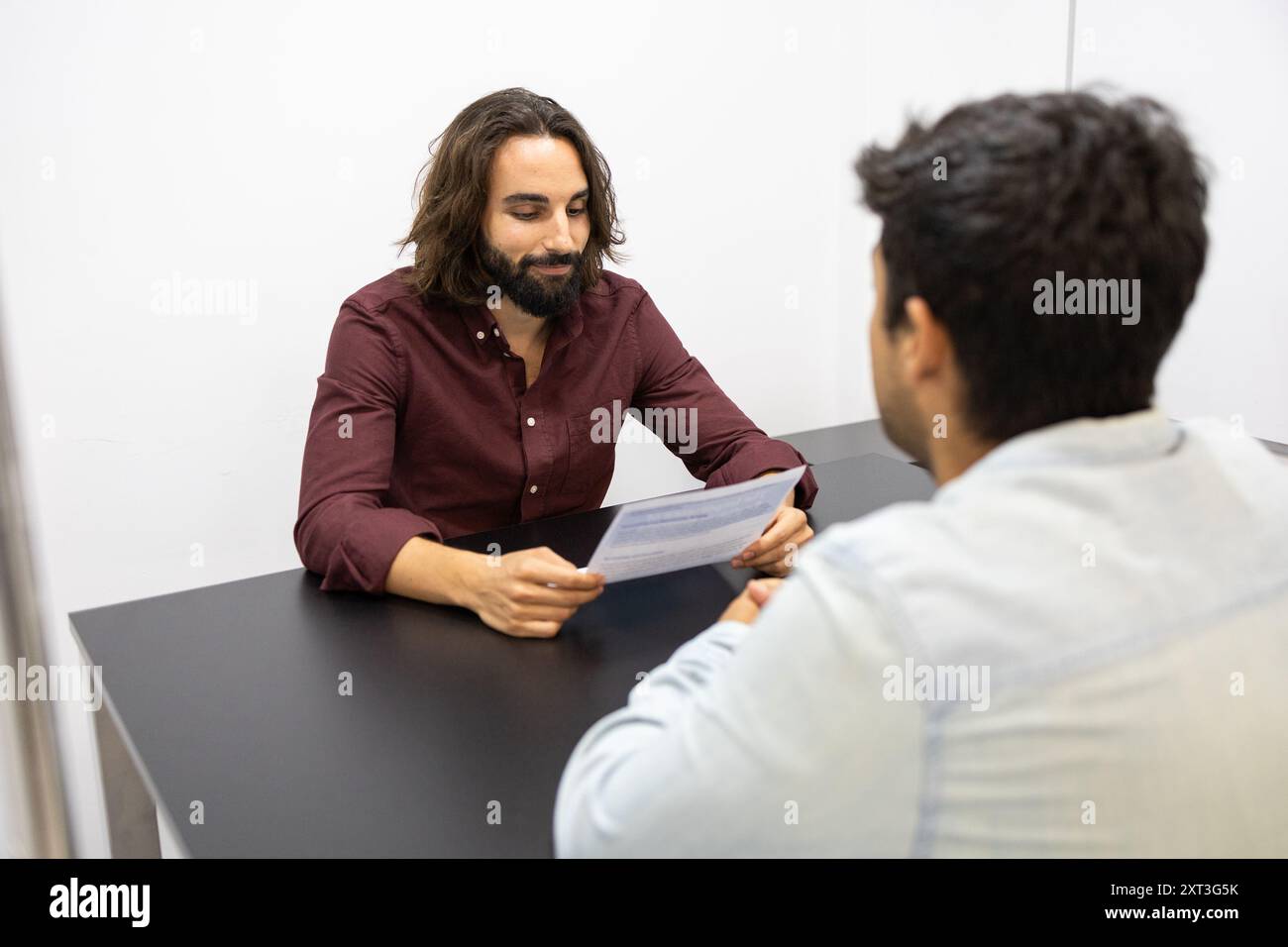 Two adult male students engage in a focused discussion over paperwork ...