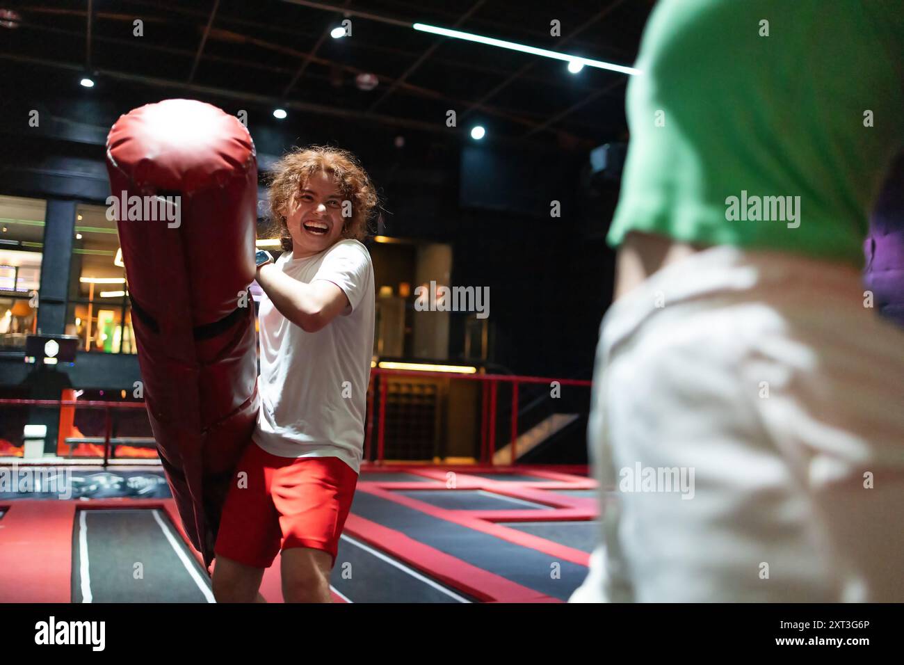 A cheerful man with curly hair, laughing as he interacts with a ...