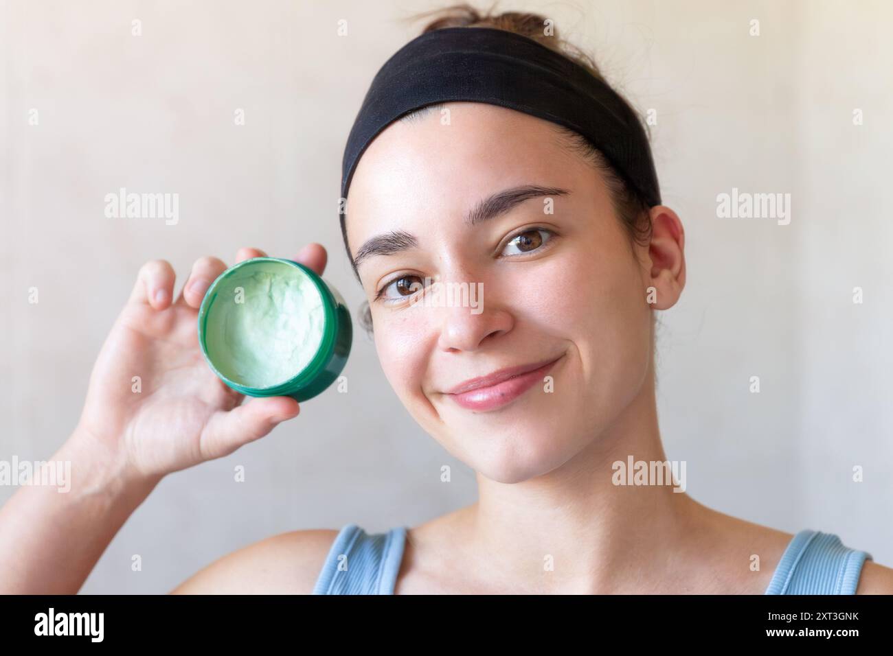 A young woman with a headband smiles as she holds an open container of ...