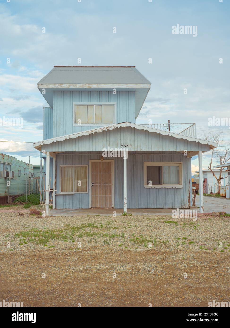 A decrepit two-story building with peeling paint, boarded-up windows ...