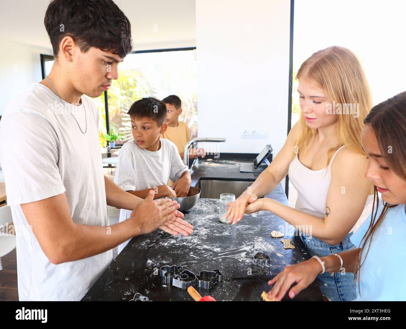 Triplets bake cookies together in a modern kitchen with their siblings ...