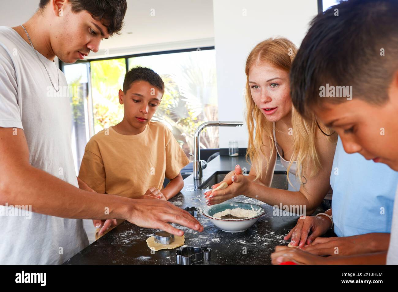 Family enjoy baking together, using cookie cutters on dough in a modern ...