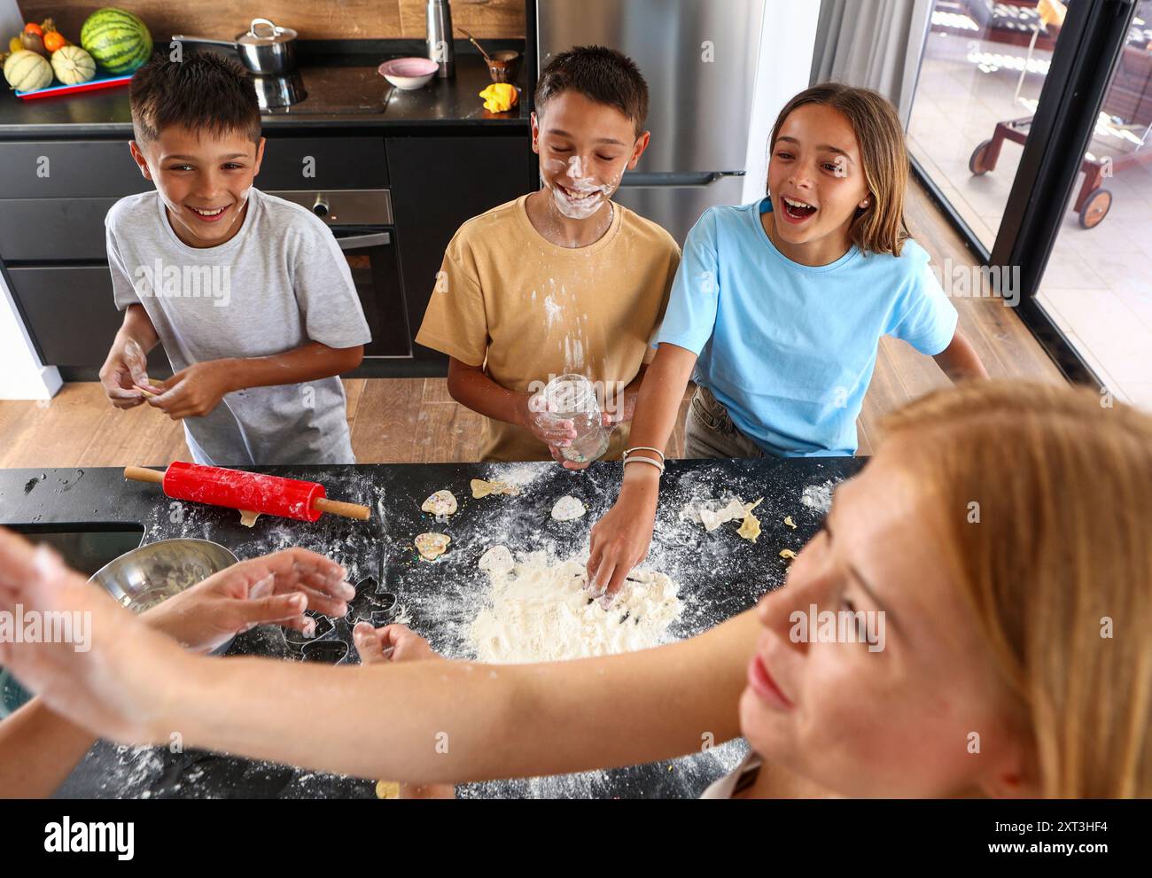 Triplets are having fun while making pastries in a modern kitchen with ...