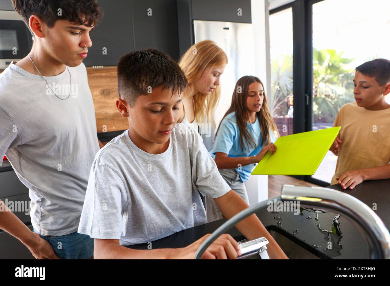 A group of siblings work together to clean up the kitchen One boy ...