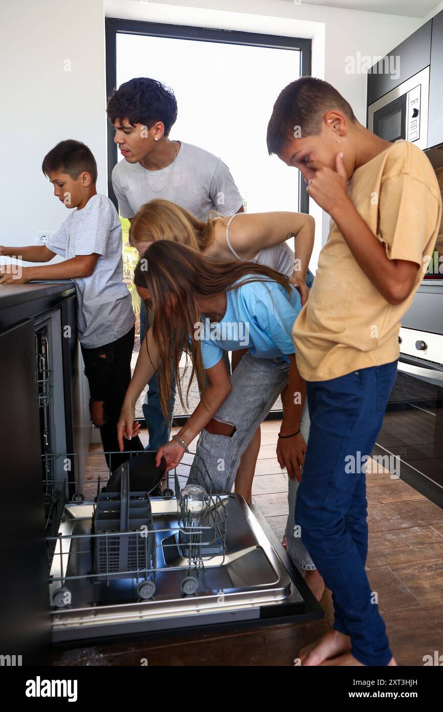 Triplets collaborate to unload a dishwasher in a sleek, modern kitchen ...