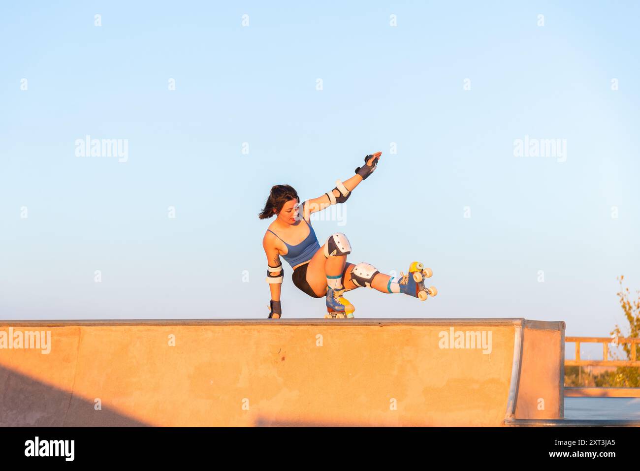 A young female skater demonstrates a dynamic pose on roller skates at a ...