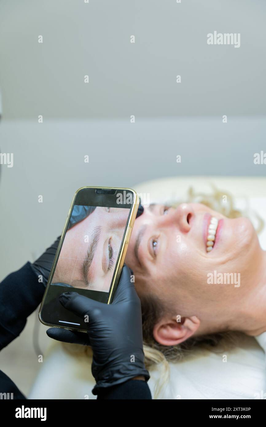 This image captures a beautician taking a close-up photo of the ...