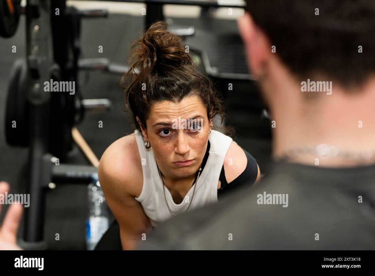 A young woman, deeply focused, prepares for a powerlifting attempt in a ...