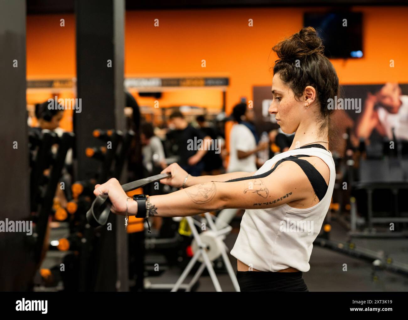 A concentrated young woman performs exercises with a stretching tape in ...
