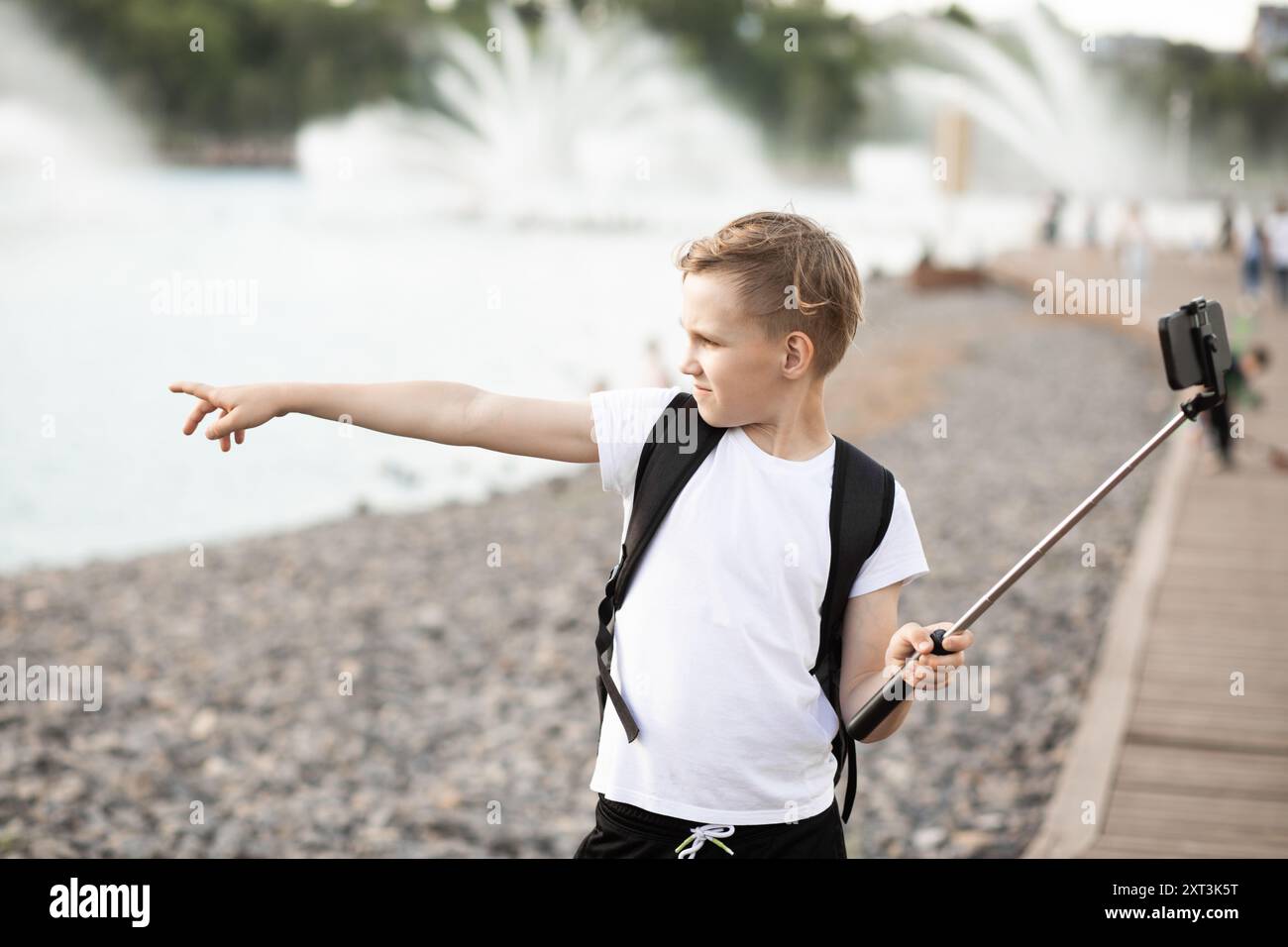 Teenager boy taking selfie outdoor in a park, using a mobile phone on a ...
