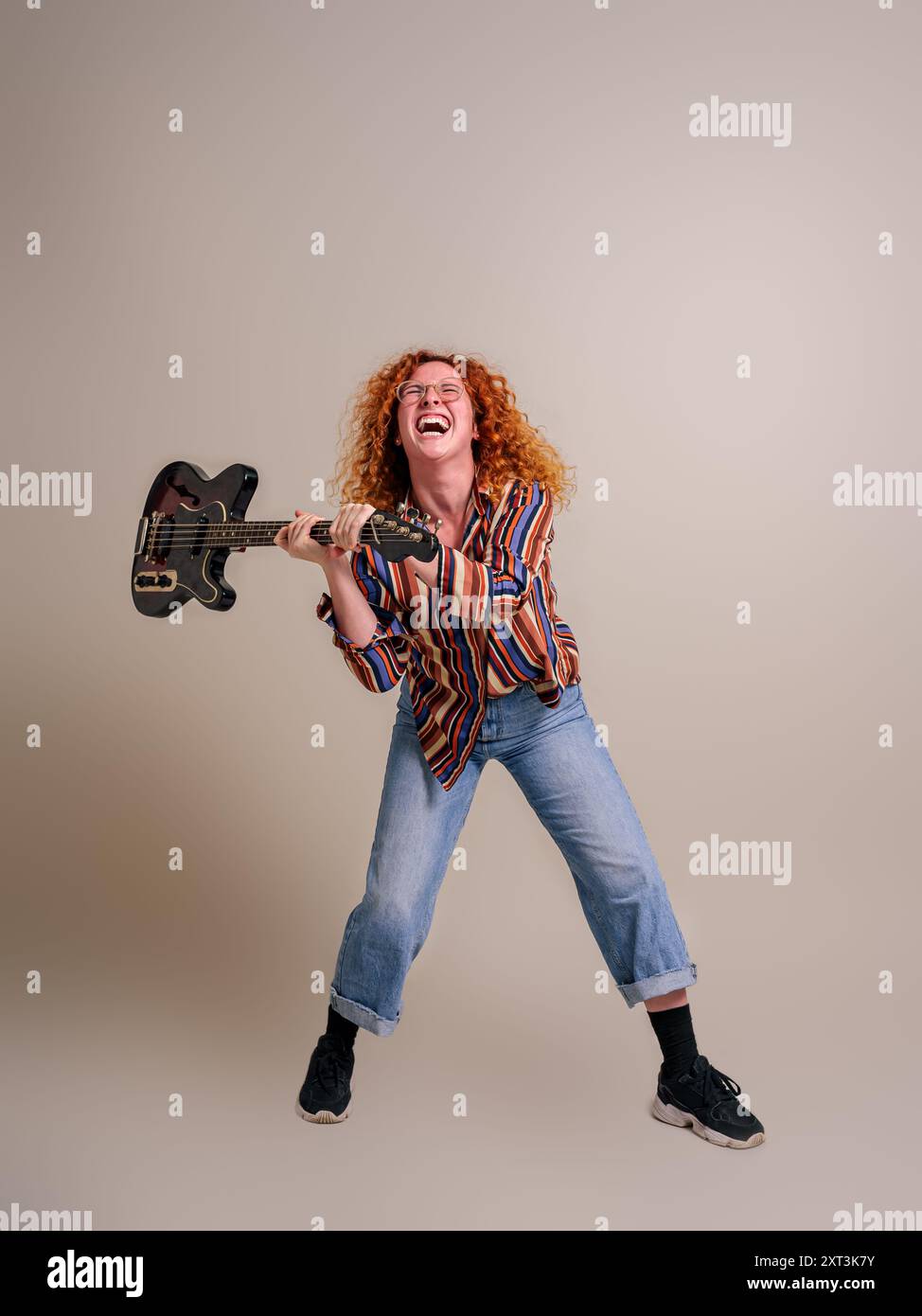 Female musician holding guitar and laughing ecstatically while standing ...