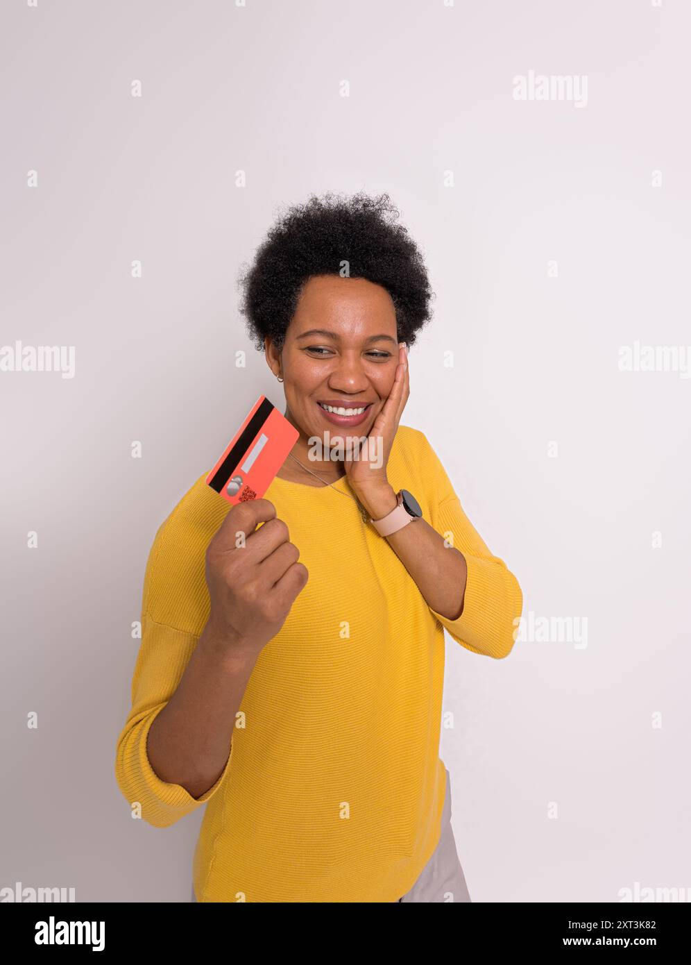 Smiling young woman touching chin and thinking while looking at credit ...