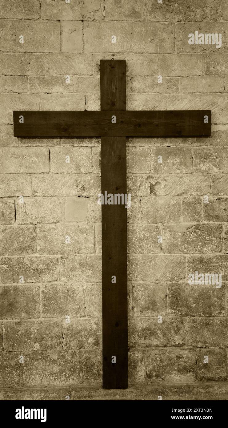 Antique wooden cross on stone brick wall of medieval church. Easter time, faith and hope. Sepia ...