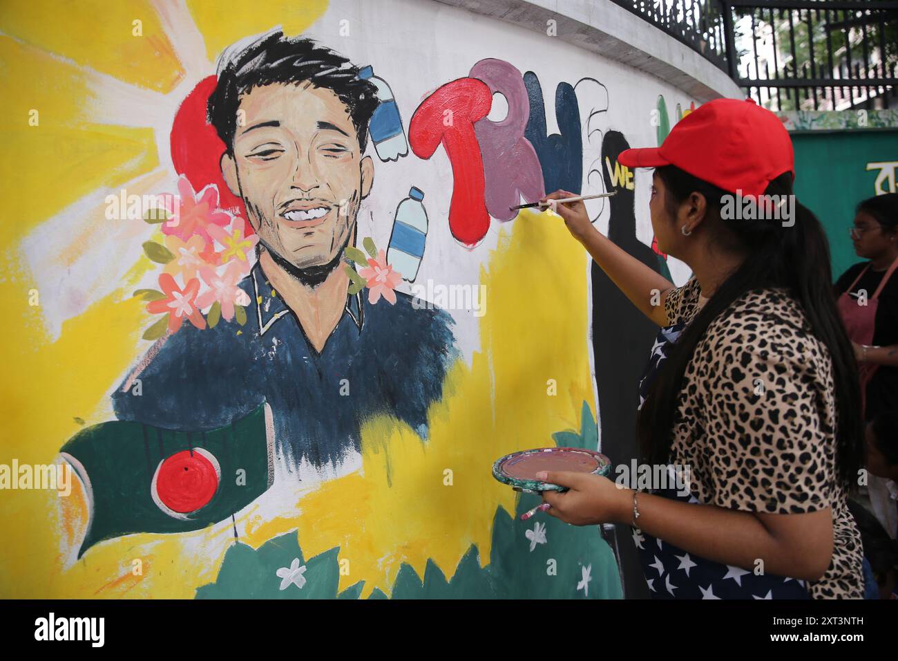 A student paints a new graffiti on a street wall at Dhaka University ...