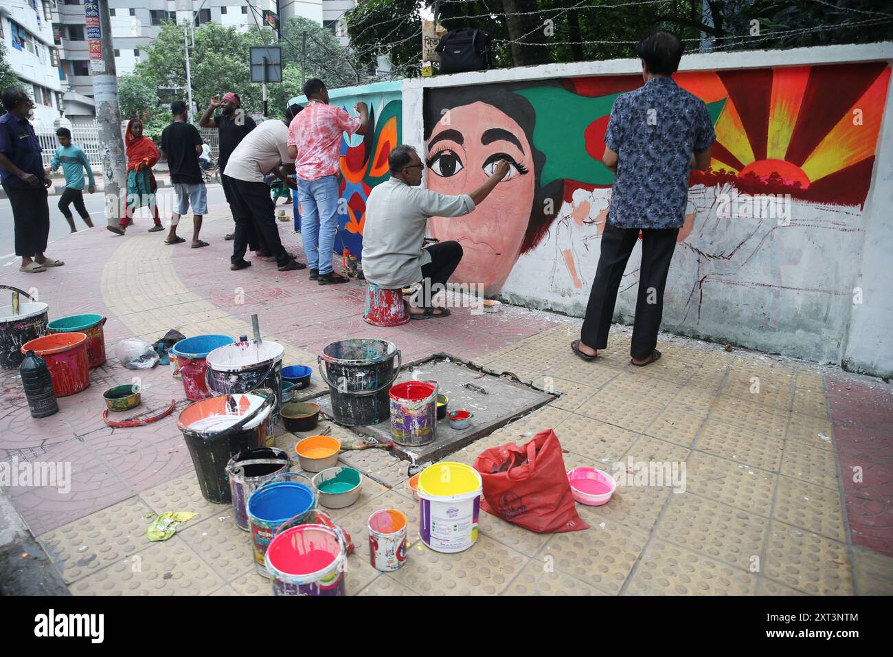 A student paints a new graffiti on a street wall at Dhaka University ...