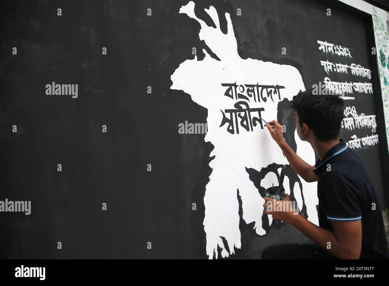 A student paints a new graffiti on a street wall at Dhaka University ...