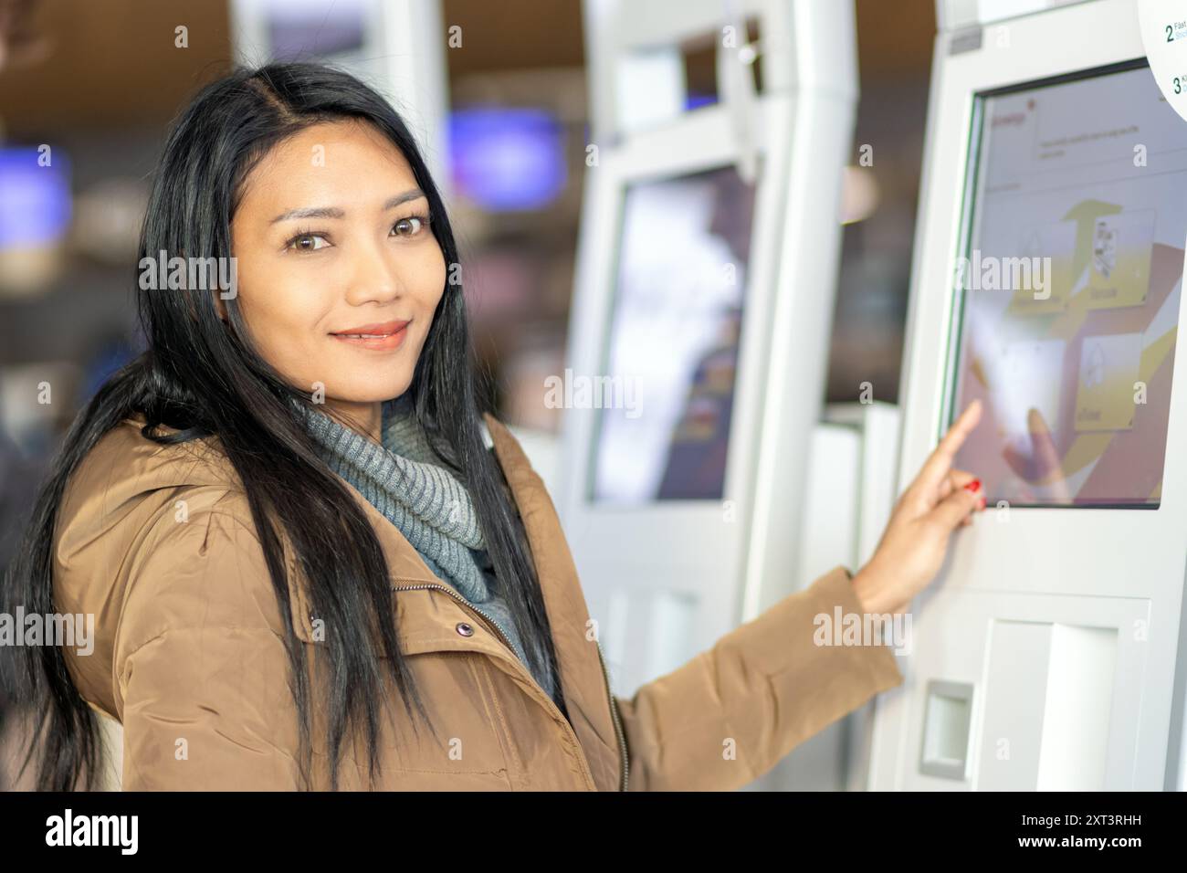 A young woman using self check-in kiosks in airport terminal Stock ...