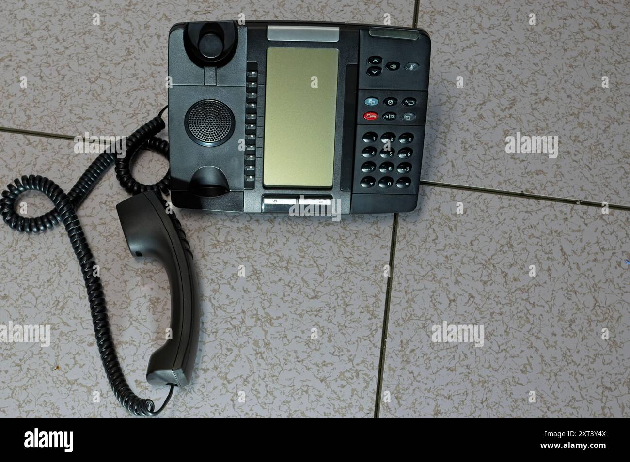 Office phone on a tiled floor with handset off hook Stock Photo - Alamy