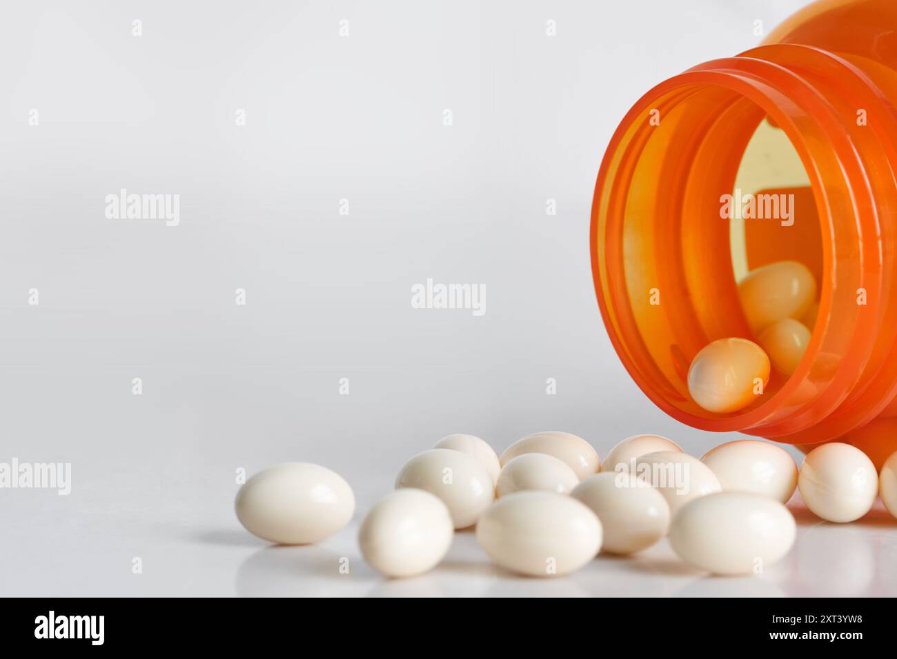 medicine bottle on its side with gel tab pills spilling out on a white ...
