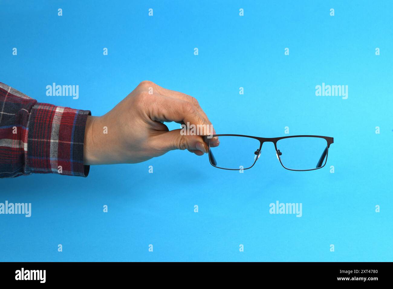 Hand holding plastic black glasses, isolated on blue background. High ...