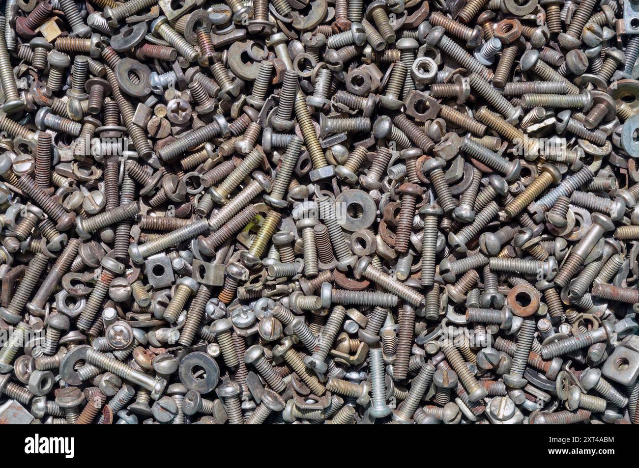 Close-up view of a chaotic assortment of various metal washers, screws, nuts, and bolts ...