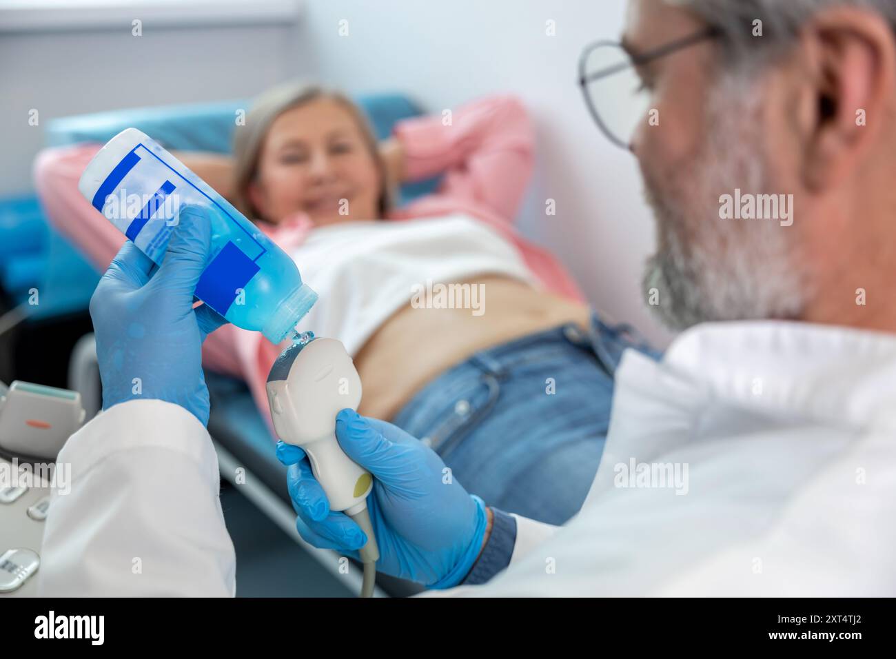 Gray-haired male doctor working with patient and making ultrasonography ...