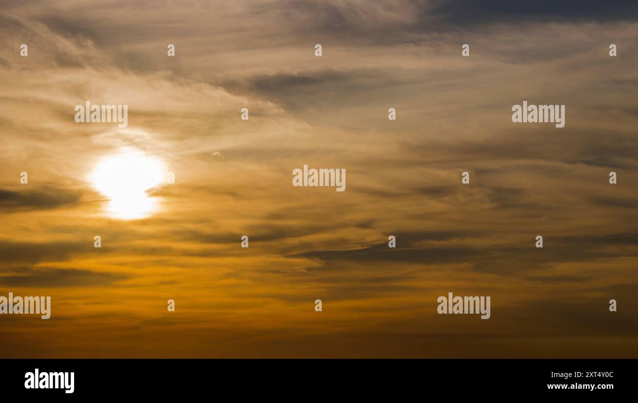 Sunset sky and the sun setting in thin clouds Stock Photo - Alamy