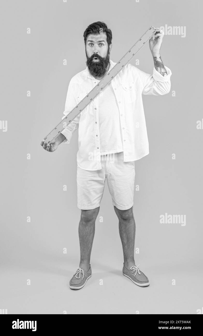 shocked man hold school ruler isolated on yellow. man hold school ruler ...