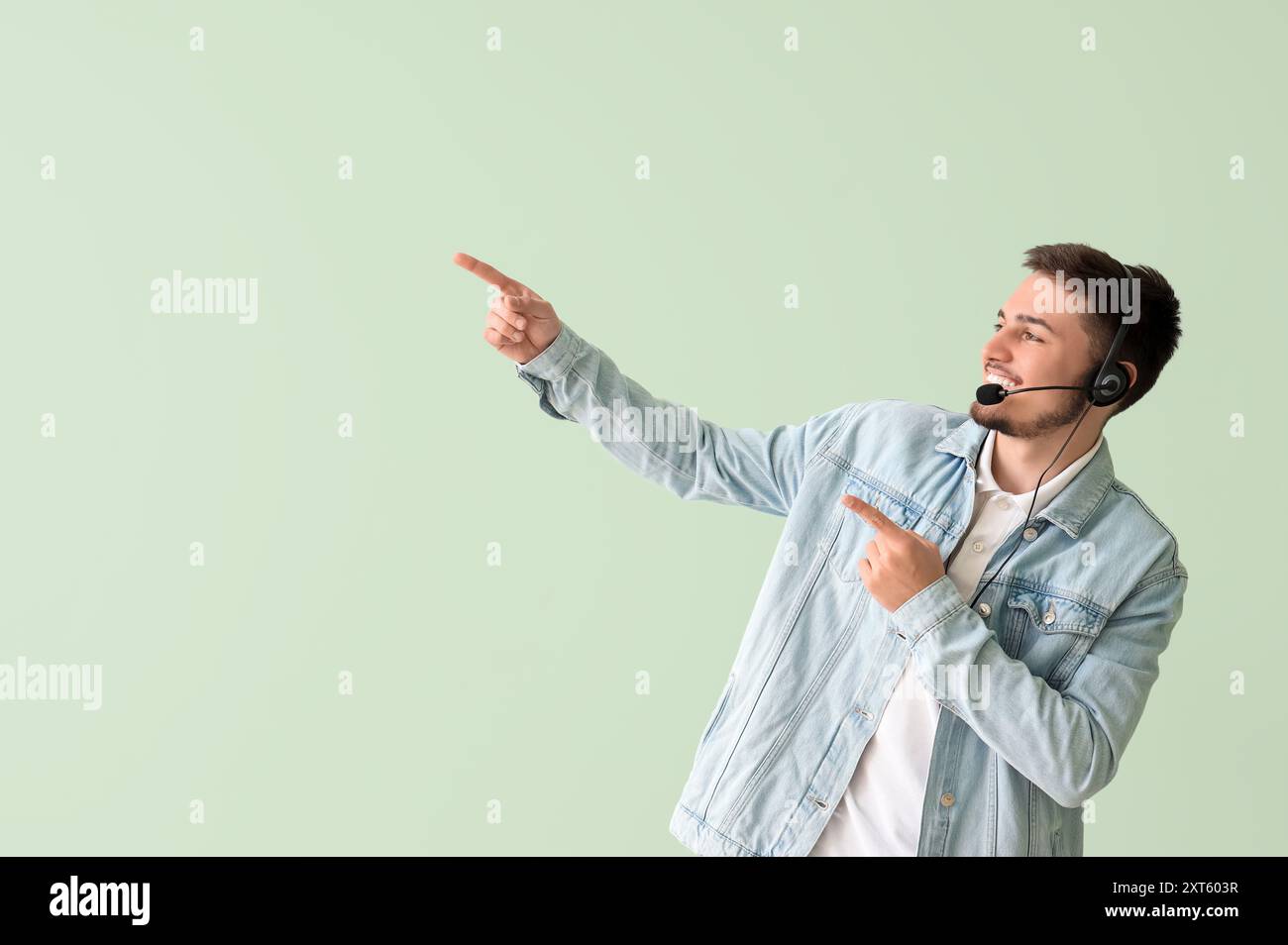Male technical support agent pointing at something on mint background ...