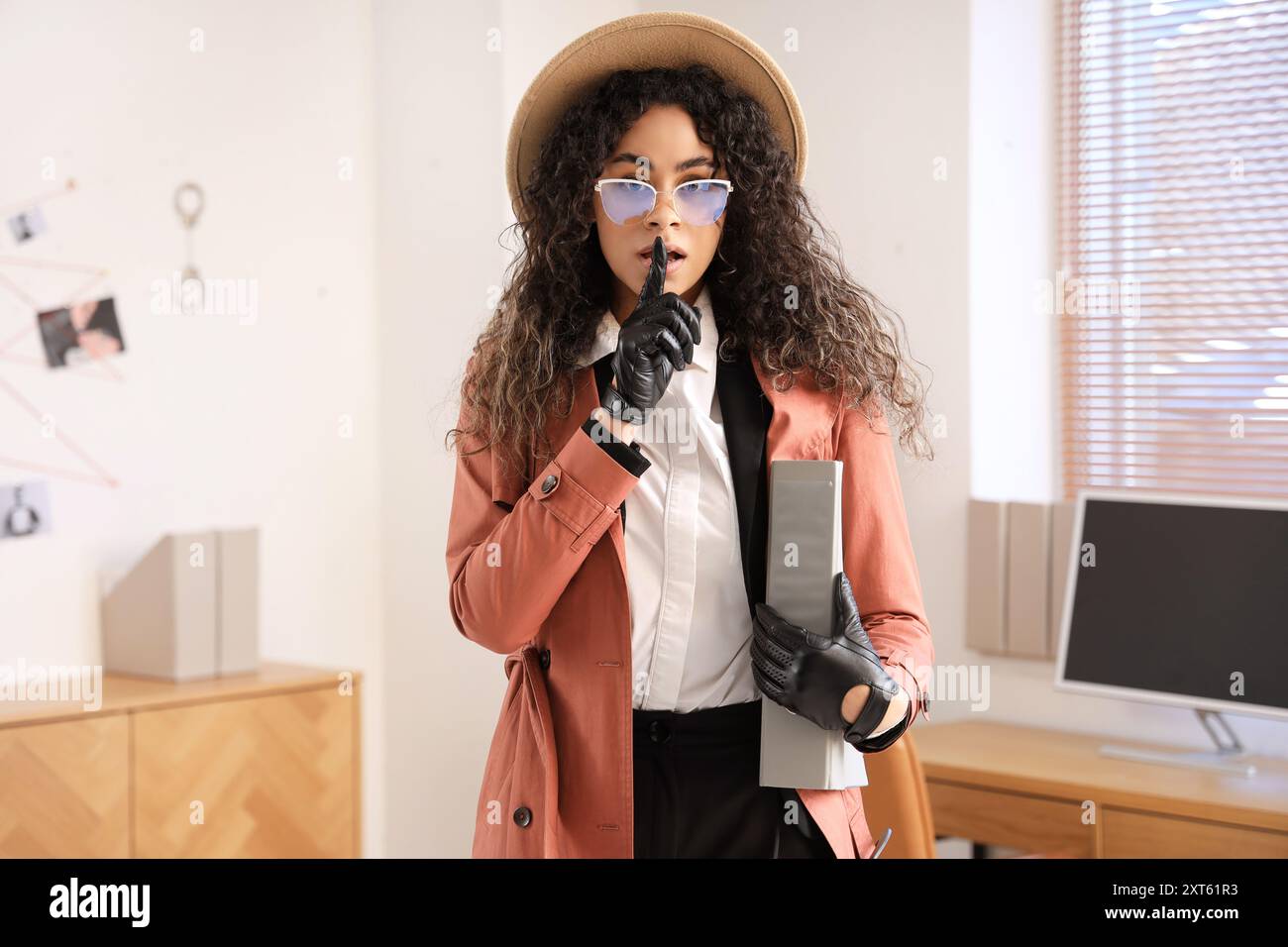 Female African-American spy with folder showing silence gesture in ...