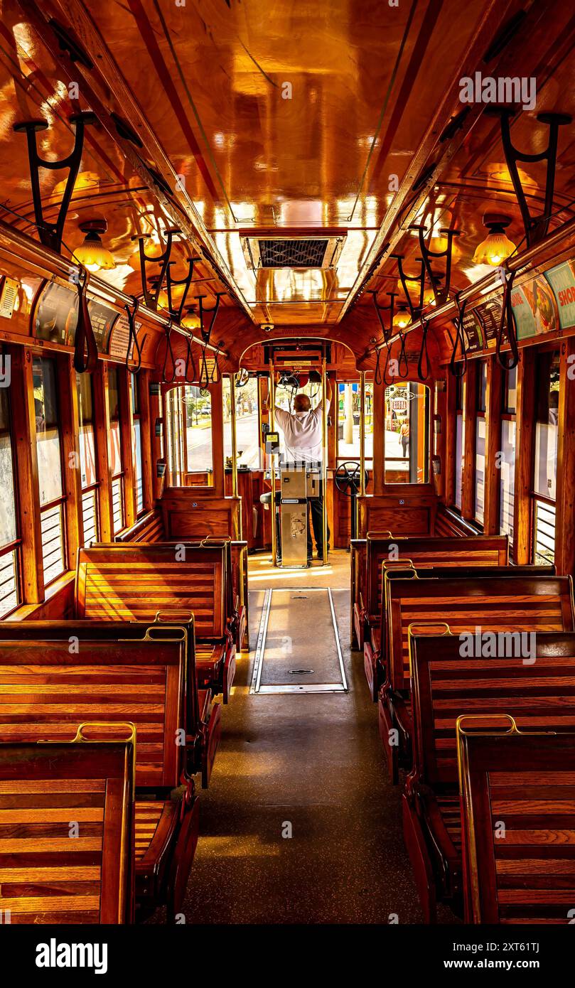 An interior view of an empty vintage tram with wooden seats and a ...