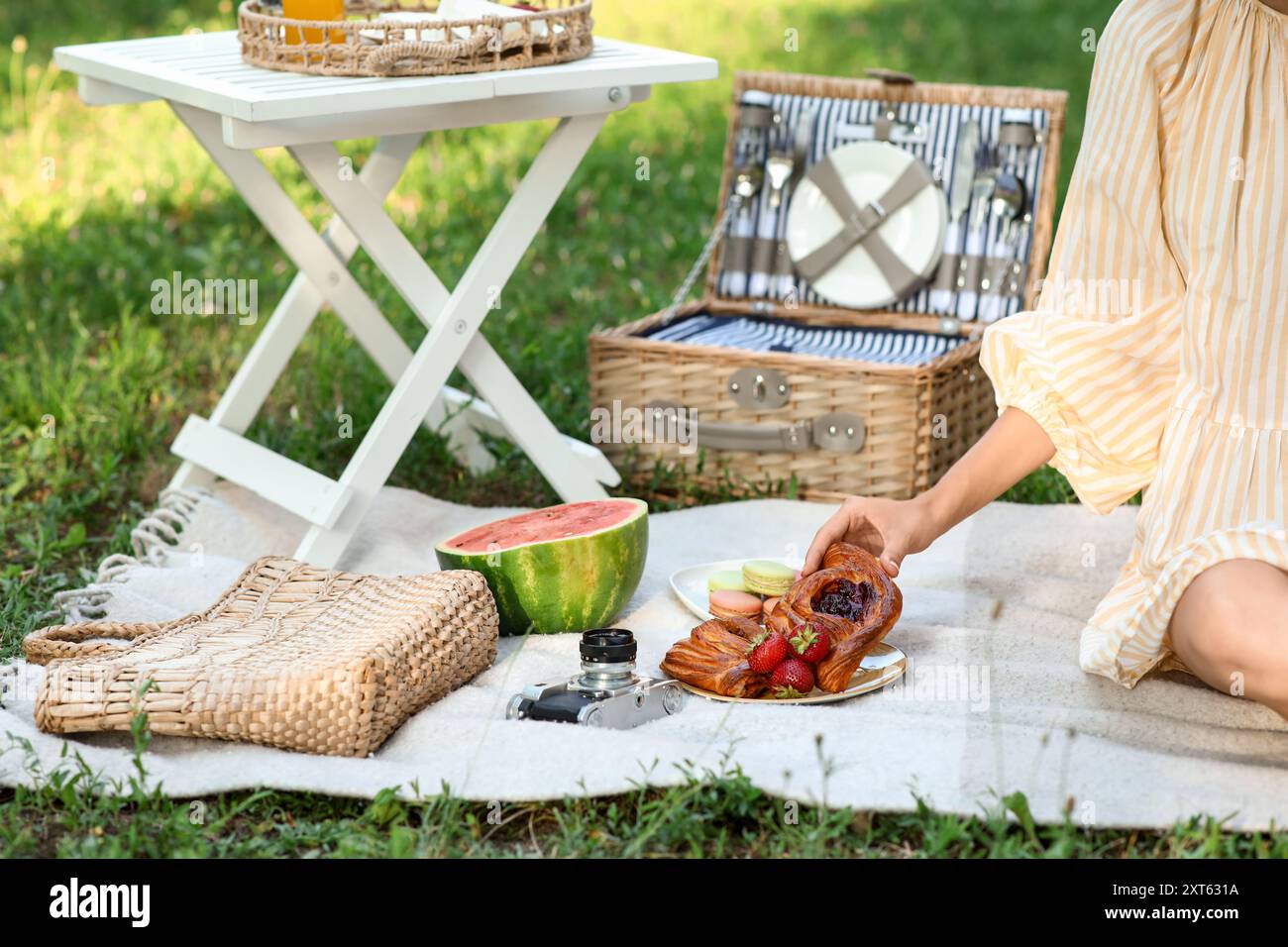 Beautiful young woman eating puff pastry at picnic in park. Closeup ...