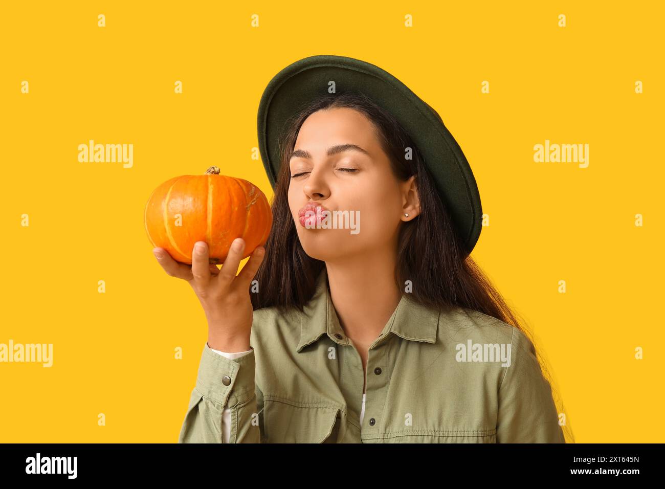Stylish young woman kissing fresh pumpkin on yellow background Stock ...