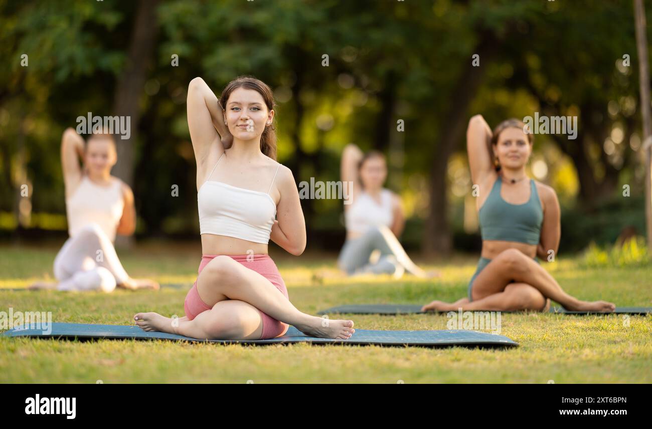 Yoga lesson visitors girls perform Gomukhasana in park Stock Photo - Alamy