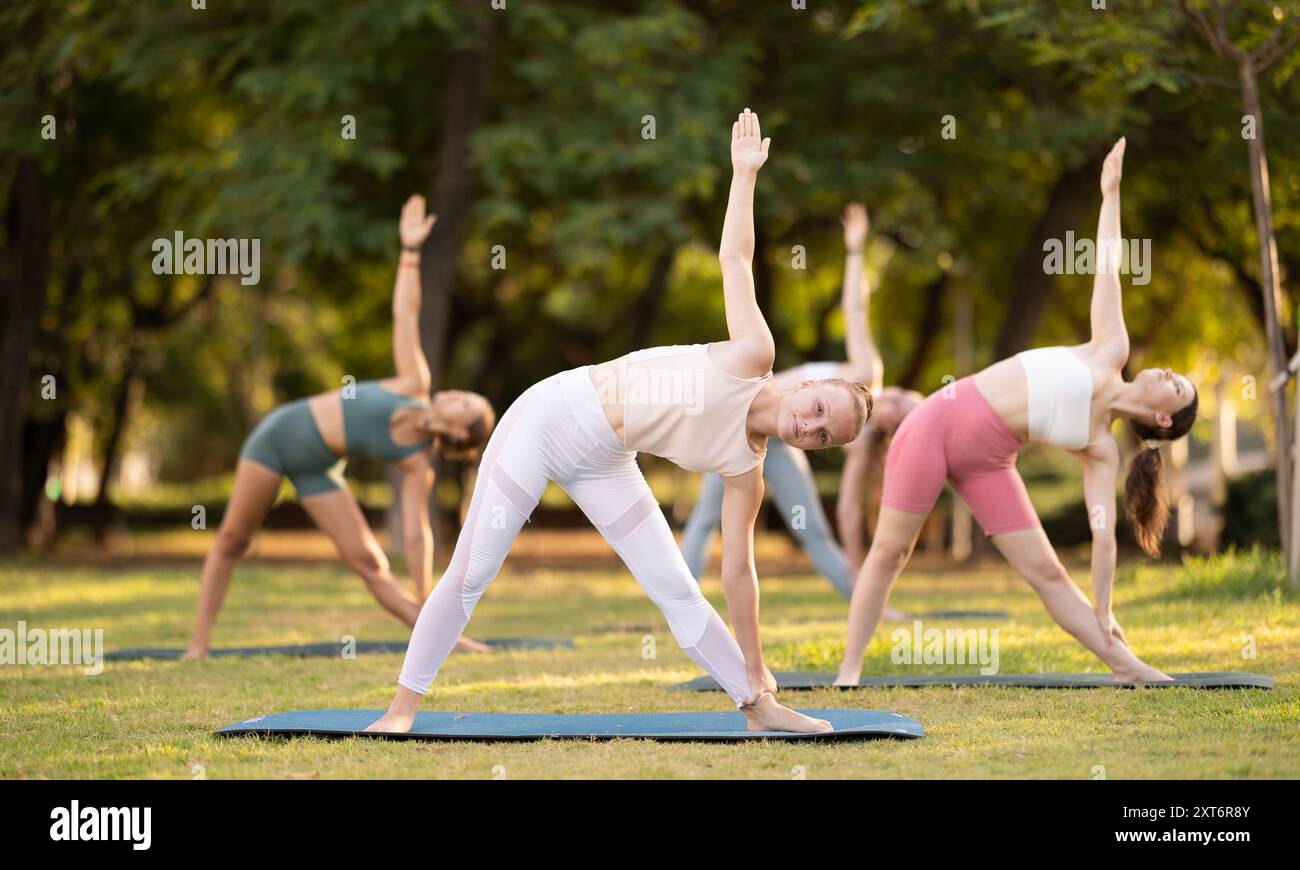 Athletic girls meditates in yoga pose parshvottanasana in summer sunny ...