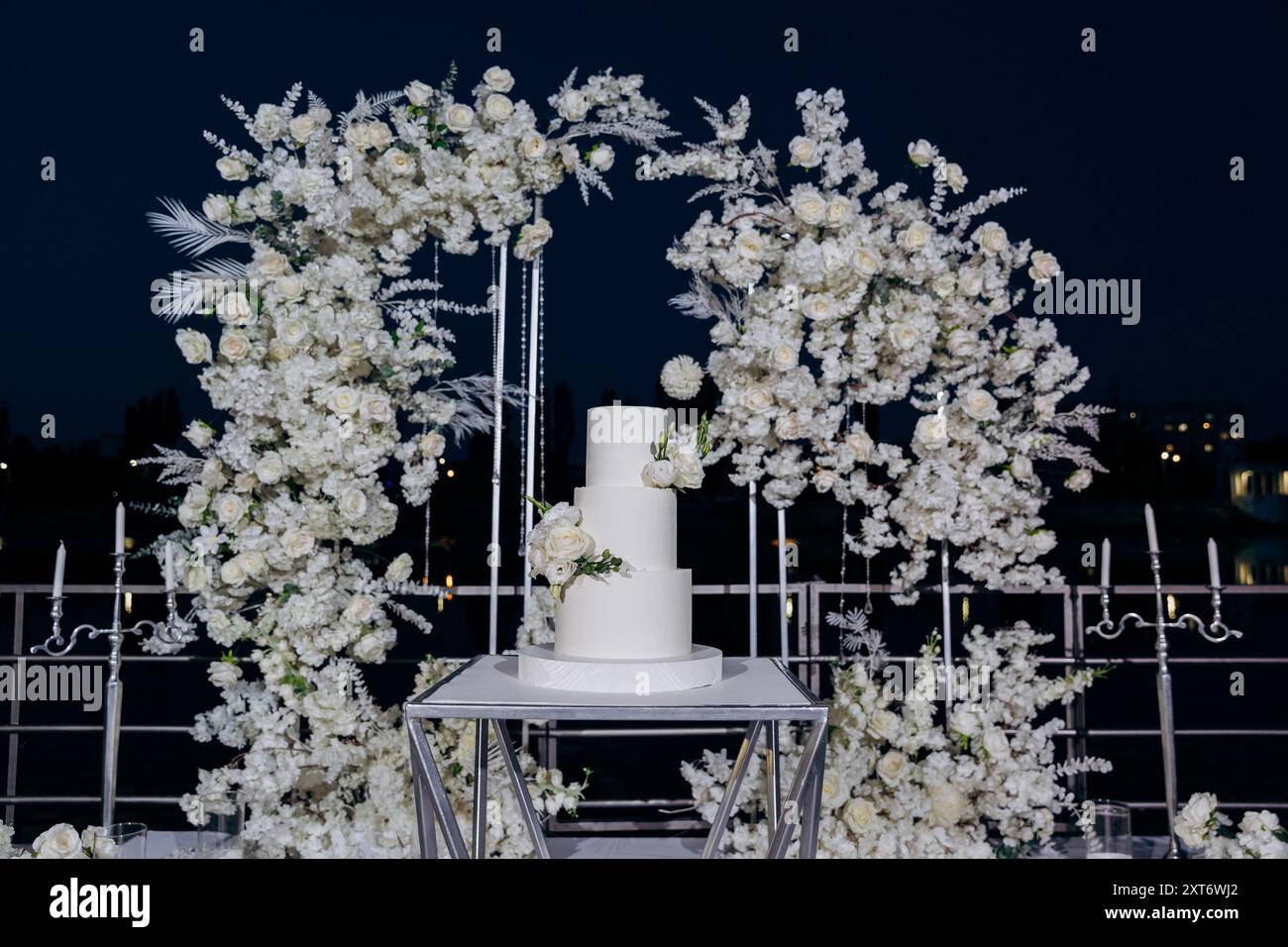 Wedding setup with three-tier white cake with floral accents. Wedding ...