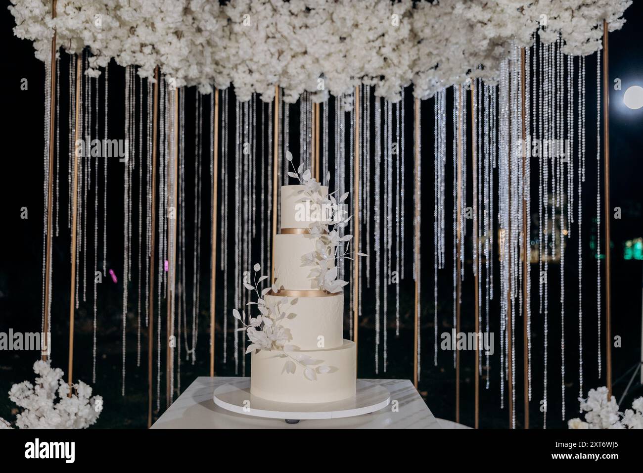 Wedding setup with three-tier white cake with floral accents. Wedding ...